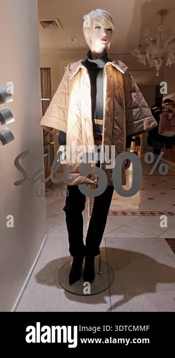 Stylish winter clothes on a mannequin behind a glass door featuring a ...