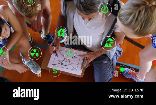 Coach kneeling drawing sports play and sparking green icons around ...