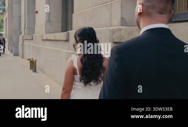 A close-up shot from behind the bride walking forward with the groom ...