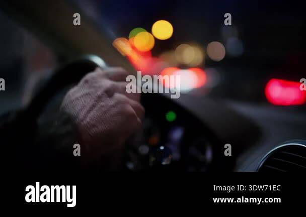 Night driving scene from inside a car with steering wheel and dashboard ...