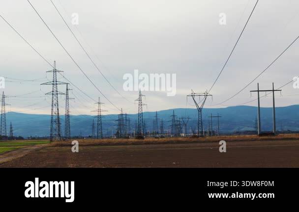 Electricity pylons and power lines stretch across fields and hills ...