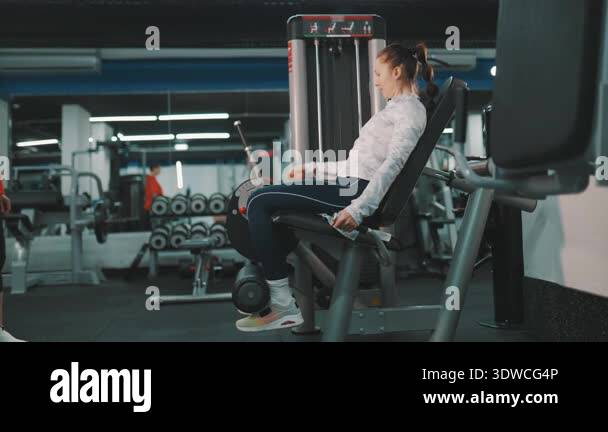 Young athletic woman performing leg extensions on a training machine ...