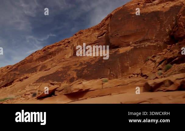 Cinematic low angle tracking shot of massive red rock mountain cliffs ...