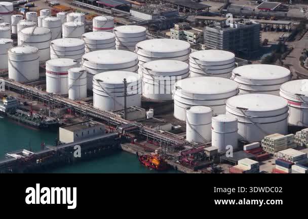 Vast industrial port with numerous white oil storage tanks and tanker ...