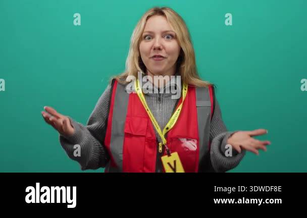 Woman volunteer standing against green background wearing red vest ...