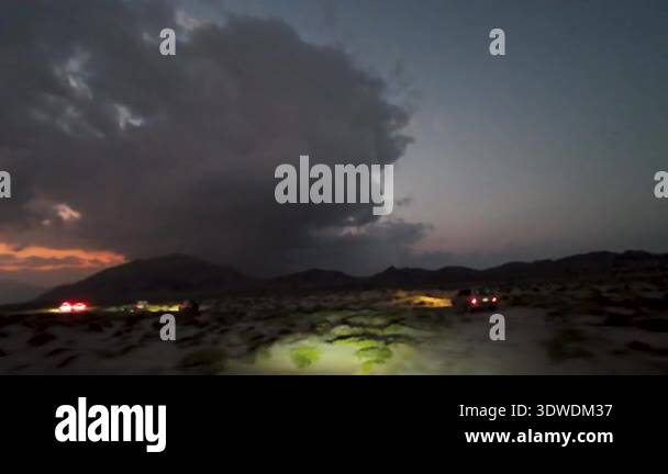 Driving through twilight desert landscape with sandy dunes and distant ...