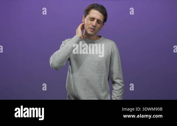 Man touching his cheek and jaw with hand in studio purple backdrop ...