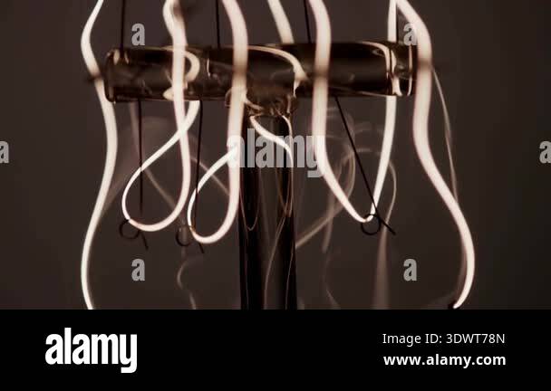 Close up shot of multiple vertical filaments inside an edison bulb ...