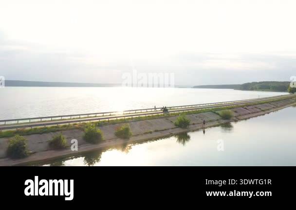 Aerial view to biker riding on motorbike at dam route with sunshine at ...