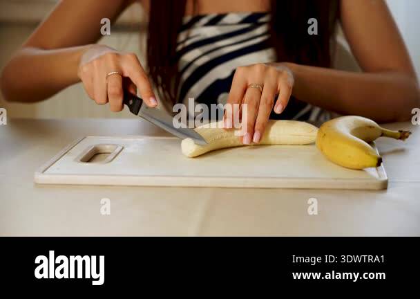 Slicing a banana in a kitchen while preparing a simple snack or meal ...