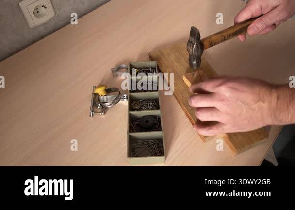 Hammer driving metal nail into wooden board close up carpentry work ...