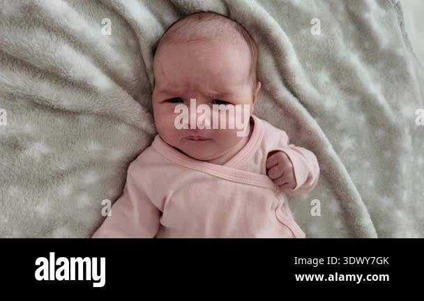 Close-up of awake newborn baby lying on blanket. Calm facial expression ...