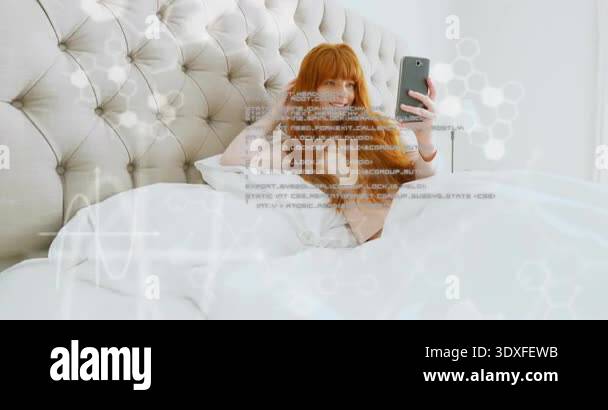 Woman lying in bed reaching for smartphone, framing face for selfie ...