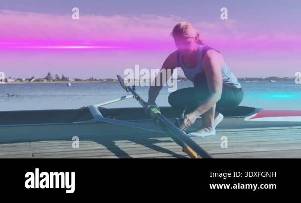Stepping onto wooden dock, mature rowing athlete kneeling and adjusting ...