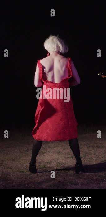 Extravagant drag queen in red dress lifts up her skirt and shows her ...