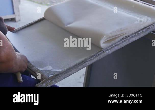 Artisan peeling dry handmade mulberry paper from wooden screen frame ...