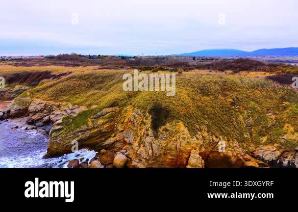 Steep rocky cliffs with green grass overlooking the sea with distant ...