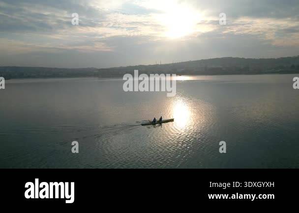 Sunrise Duo Paddling Across Shimmering Lake With Strong Sun Reflection ...