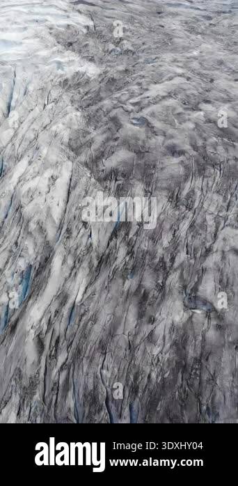 Dramatic aerial view flying over a vast and heavily crevassed gray ...