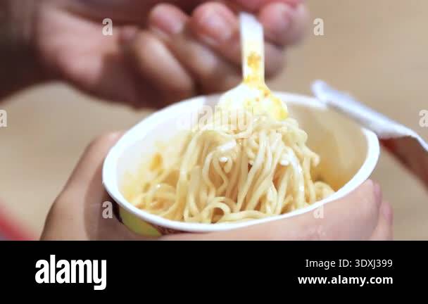 Hands twirling pasta noodles in a bowl with a fork. close-up. Focus on ...