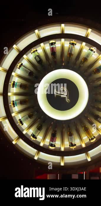 Circular wine rack showcasing various wine bottles, illuminated by ...