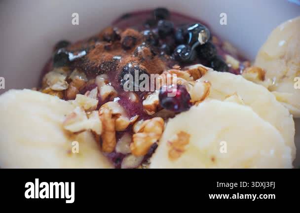 Macro slow motion cinnamon sprinkle over oatmeal with fruit and nuts ...