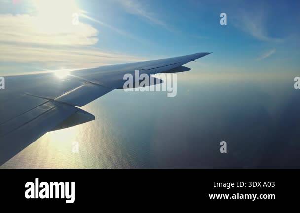 Beautiful view of airplane wing flying over Caribbean Sea at sunset ...