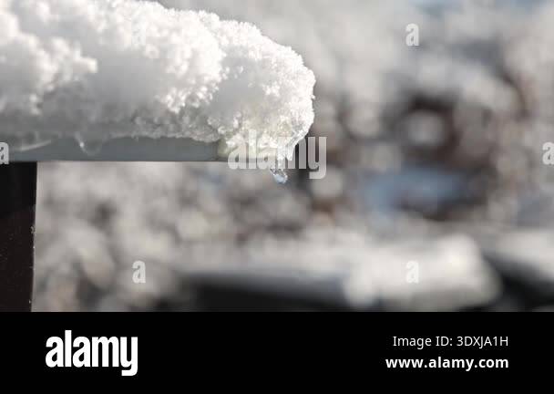 Close up view of melting snow as water droplets drip from metal edge in ...
