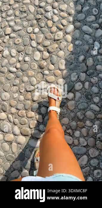 Top view of person walking on cobblestone pavement in sandals. High ...