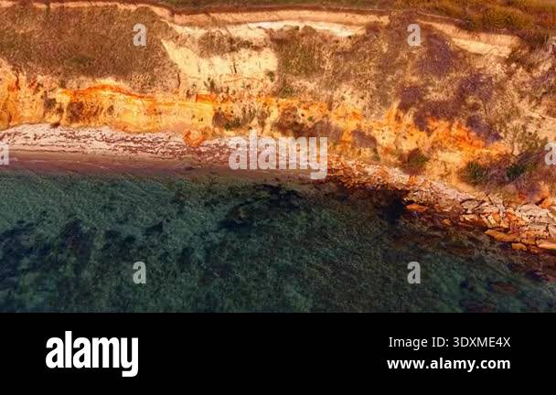 High angle view of rocky cliffs meeting clear sea water. Top-down ...