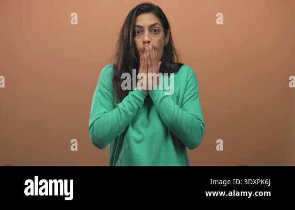 Young hispanic woman with hands on cheeks and open mouth in studio ...