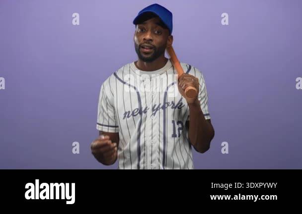 Man wearing pinstripe jersey and blue cap holding baseball bat over ...