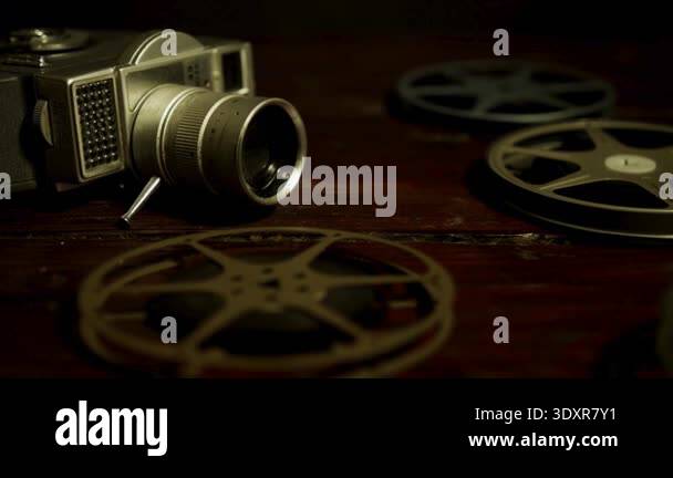 Vintage silver movie camera and old film reels lying on dark wooden ...