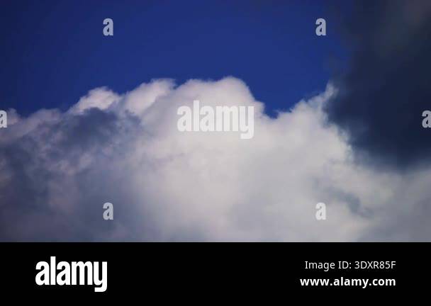 Massive white cumulus clouds building up against a vibrant blue sky ...