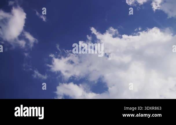 Sparse white clouds floating in a bright blue sky on a clear day with ...