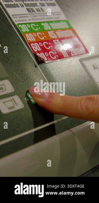 Close-up view of a hand activating a washing machine control panel ...