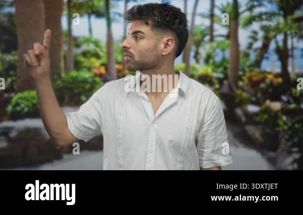 Man with finger pointing right at walking path in green park under palm ...