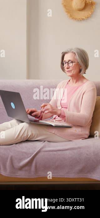 Mature old 60s woman student working at home using laptop technology ...