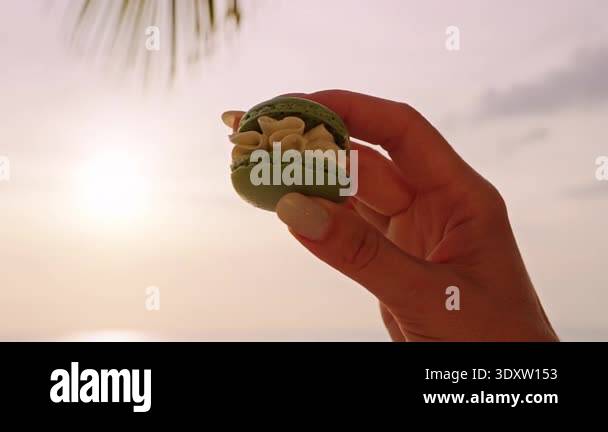 Female Hand Holding Green Macaron Against Sunset Sky Creating Elegant ...