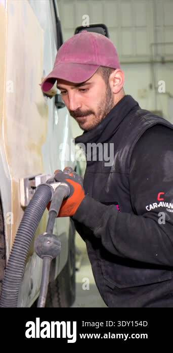 Professional mechanic in a garage using an electric sander to smooth ...
