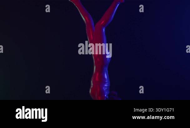 Female acrobat in a shiny bodysuit performs a dramatic handstand split ...