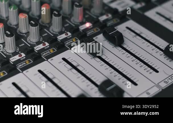 Macro of an audio producer's fingers moving a volume fader up and down ...