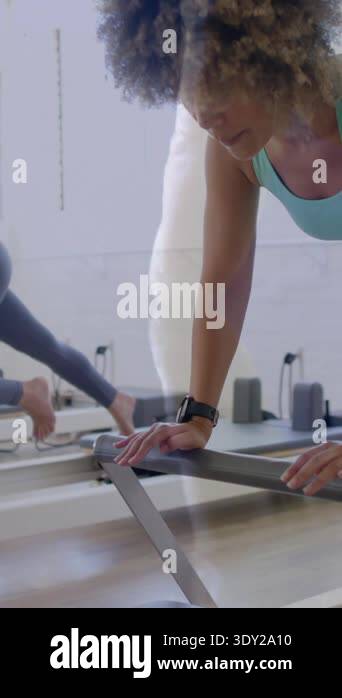 Women exercising on reformer machines with digital data overlay ...
