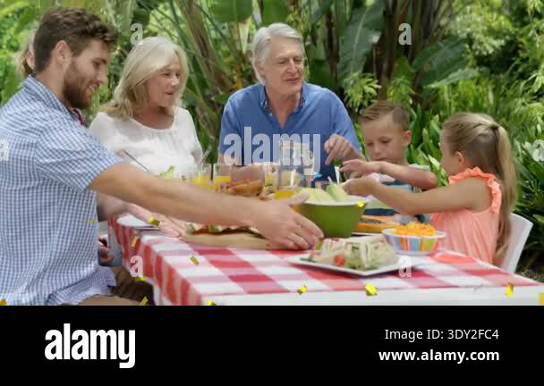 Man sliding platter onto table and spurring family serving salad amid ...