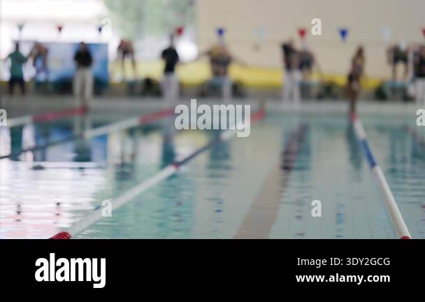 Athletes diving into a swimming pool to start a race, with intentional ...