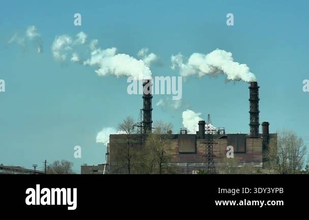 Industrial smokestacks releasing thick white smoke above factory ...