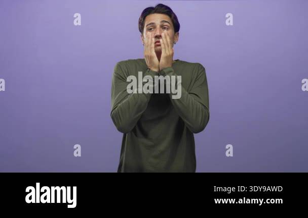 Man cupping cheeks with both hands and pursing lips while standing ...