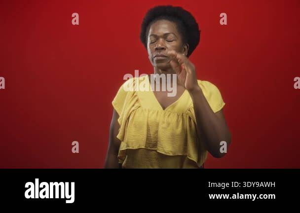 Woman touching ear in studio wearing yellow blouse and afro, attentive ...