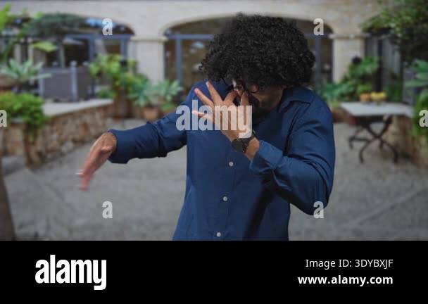 Man pinching his nose with hand and glasses in a building courtyard ...