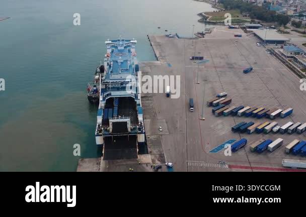 Ferry ship at a harbor terminal with trucks boarding through the stern ...